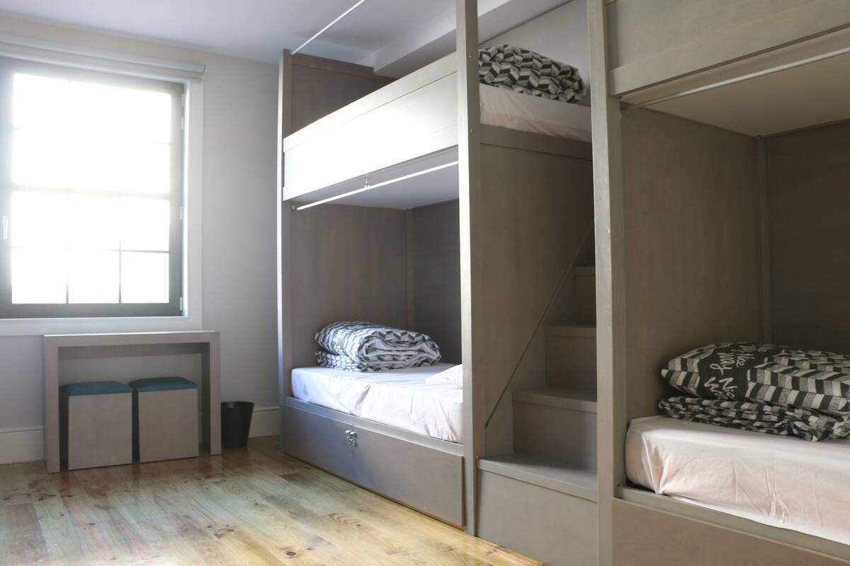 Quarto com beliche, escrivaninha e janela.