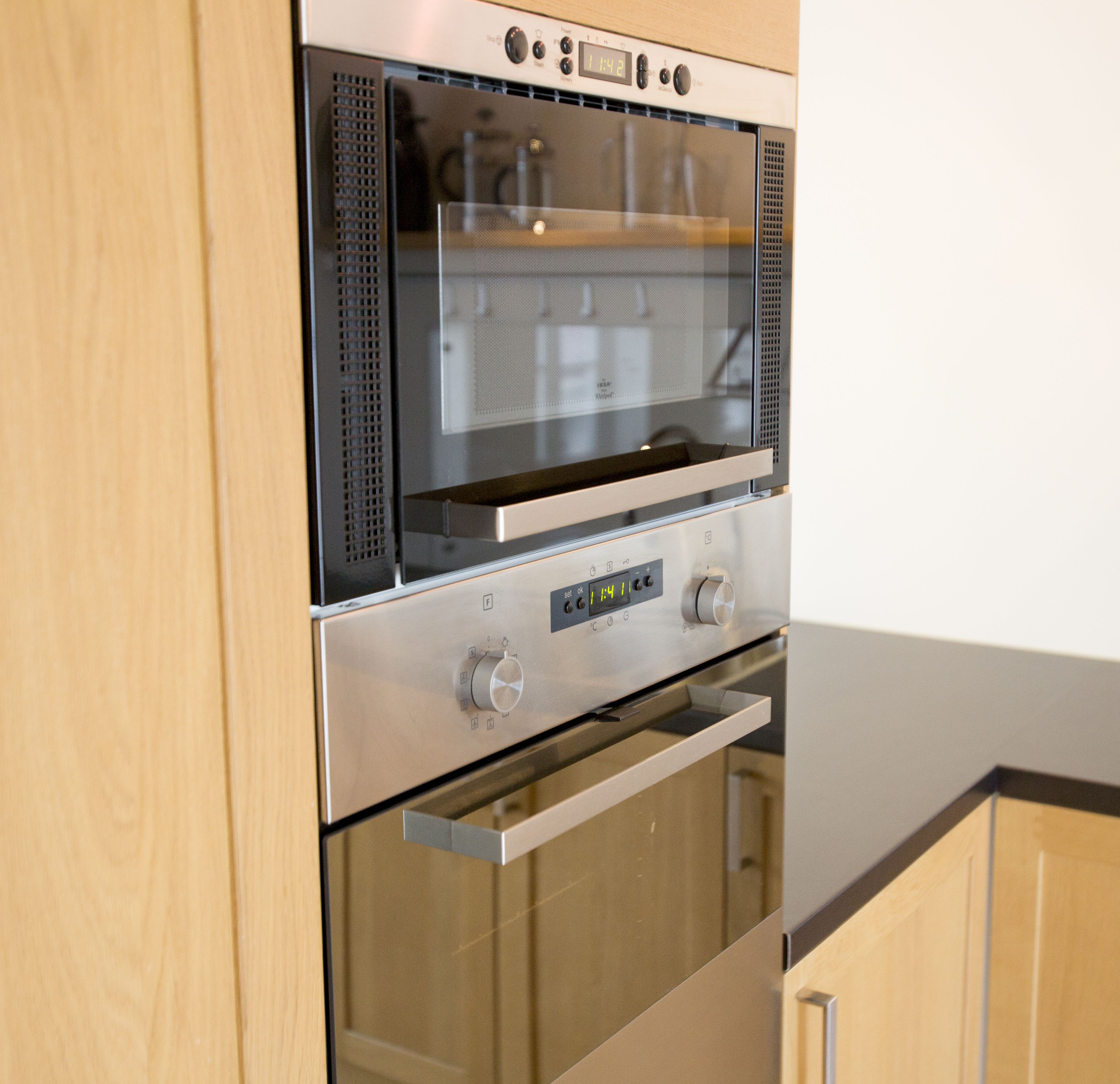 Um forno de aço inoxidável com visor digital, painel de controle e porta de vidro.