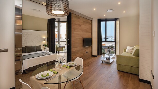 Quarto de hotel moderno com área de refeições, cama, sofá e televisão.