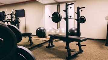 Uma academia com equipamentos de musculação, um banco e bolas de exercício.