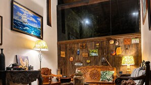 Uma sala de estar aconchegante com mobiliário de madeira, uma janela grande e diversas decorações nas paredes.