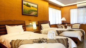 Quarto de hotel com duas camas, um quadro na parede e uma janela com cortinas.