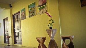 Um corredor com mobiliário de madeira, uma planta em vaso e obras de arte nas paredes.