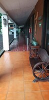 Um corredor com chão de azulejos, um banco e um extintor fixado na parede.