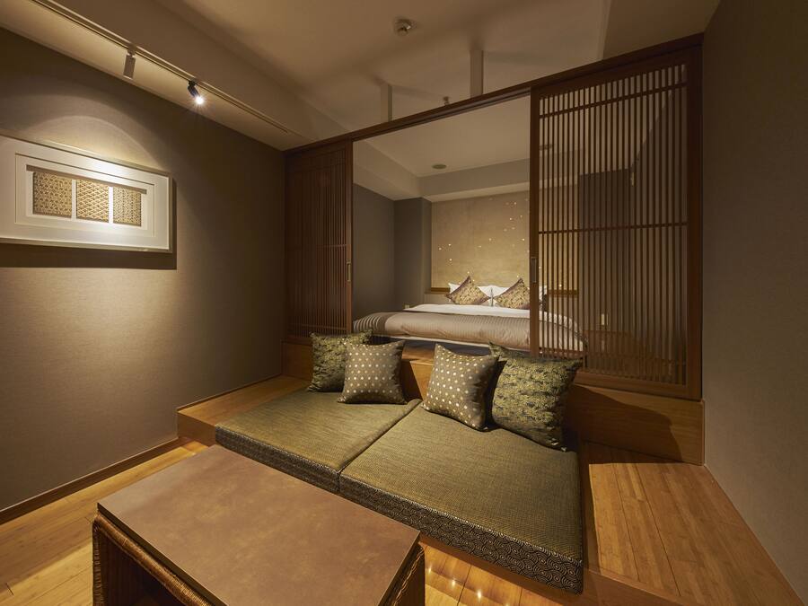 Um quarto tradicional japonês com tatames, futon em plataforma baixa e biombos shoji.