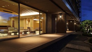 Exterior moderno de hotel à noite, com área externa bem iluminada e um caminho que leva à entrada.