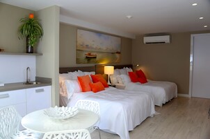Quarto de hotel com duas camas, uma mesa de jantar e uma cozinha.