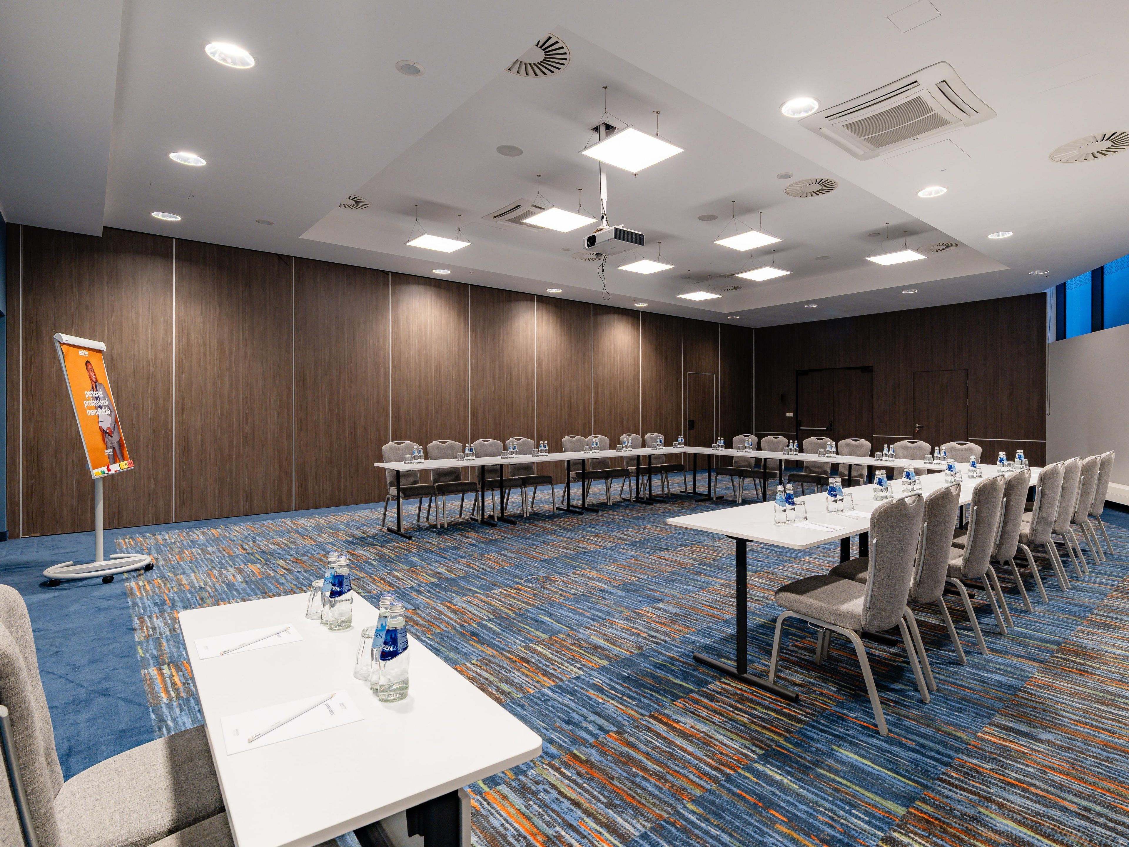 Uma sala de conferências com uma mesa comprida, cadeiras e piso coberto de carpete.