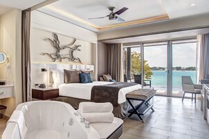 Quarto de hotel moderno com uma cama grande, área de estar, banheira e varanda com vista para o mar.