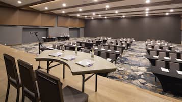 Sala de conferência com várias mesas e cadeiras, equipada com laptops, garrafas de água e porta-nomes.