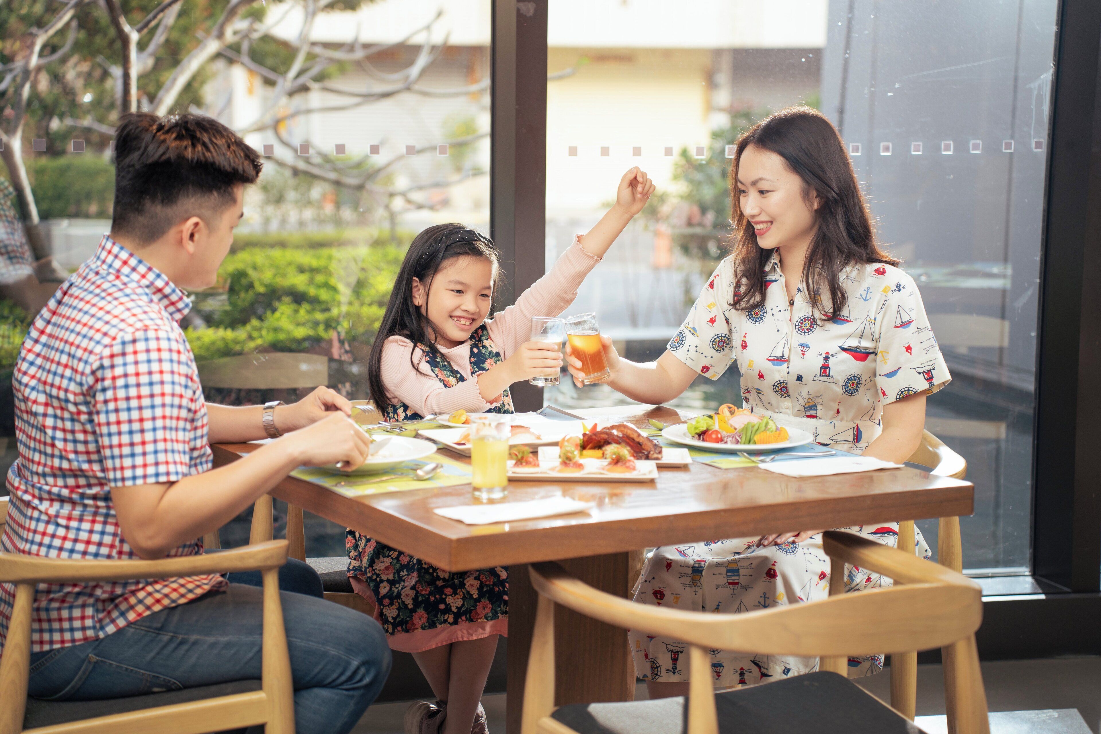 Uma família jantando à mesa com vista para o verde lá fora.