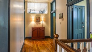 Um corredor com piso de madeira, uma porta azul e um armário com duas luminárias.