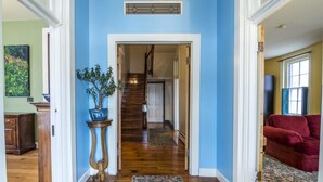 Um corredor com piso de madeira, parede azul e escada que leva a outro cômodo.
