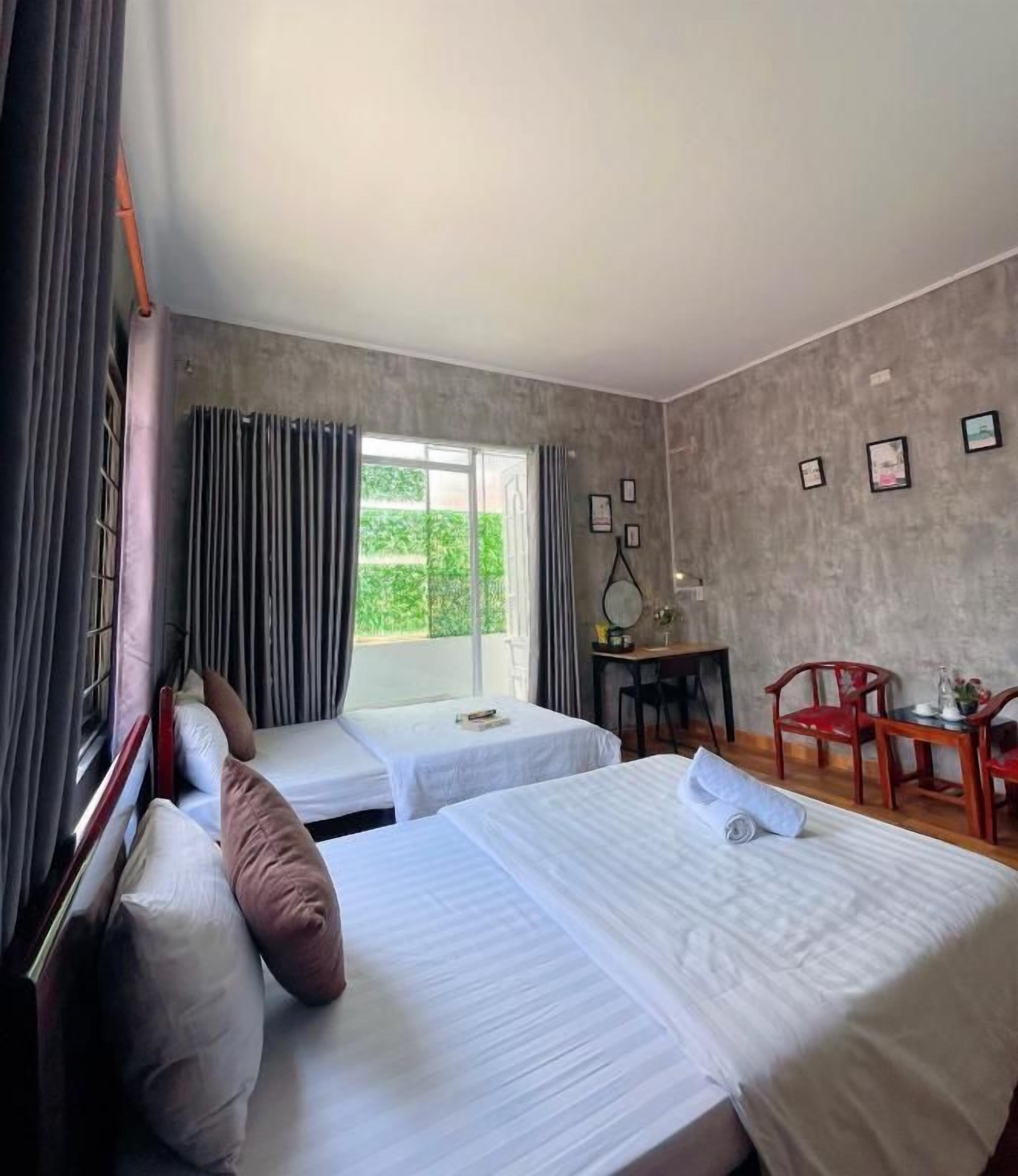 Quarto de hotel com duas camas, uma mesa e uma cadeira.