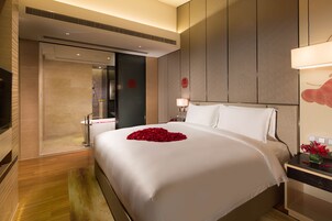 Quarto de hotel moderno com uma cama grande, televisão e banheiro com chuveiro.