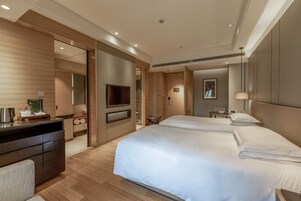 Quarto de hotel moderno com uma cama grande, televisão, escrivaninha e closet espaçoso.
