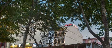 Um café com letreiro de neon, rodeado por árvores e edifícios.