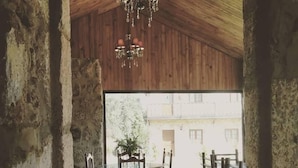 Decoração rústica com teto de madeira, um candelabro e um espaço de jantar com cadeiras e uma mesa.