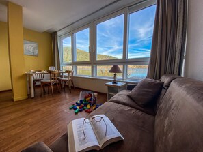 Uma sala de estar aconchegante com uma janela grande, móveis de madeira e vista para um lago.