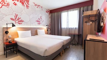 Quarto de hotel com cama grande, mesas de cabeceira, escrivaninha, televisão e janela com cortinas.