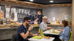 Espaço de café da manhã com máquina de café, assentos e um quadro de cardápio.