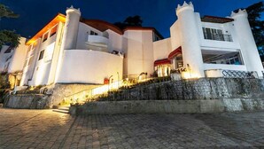 Um edifício moderno com fachada branca, várias varandas e uma escadaria de pedra que leva à entrada.