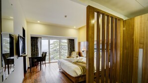 Quarto de hotel com uma cama grande, uma escrivaninha e vista para o exterior.