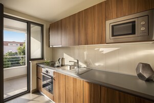 Cozinha moderna com armários de madeira, pia de aço inoxidável e micro-ondas embutido.
