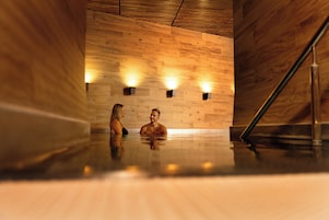 Uma sauna com paredes de madeira e chão polido, com duas luminárias fixadas na parede.