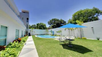 Um edifício moderno com piscina, área de estar externa e um gramado bem cuidado.