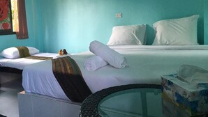 Quarto de hotel com duas camas, uma mesa de vidro e uma janela com cortina.
