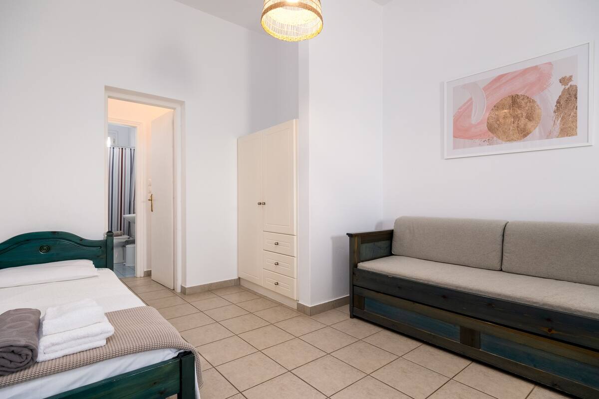 Quarto com cama, sofá, guarda-roupa e um quadro na parede.