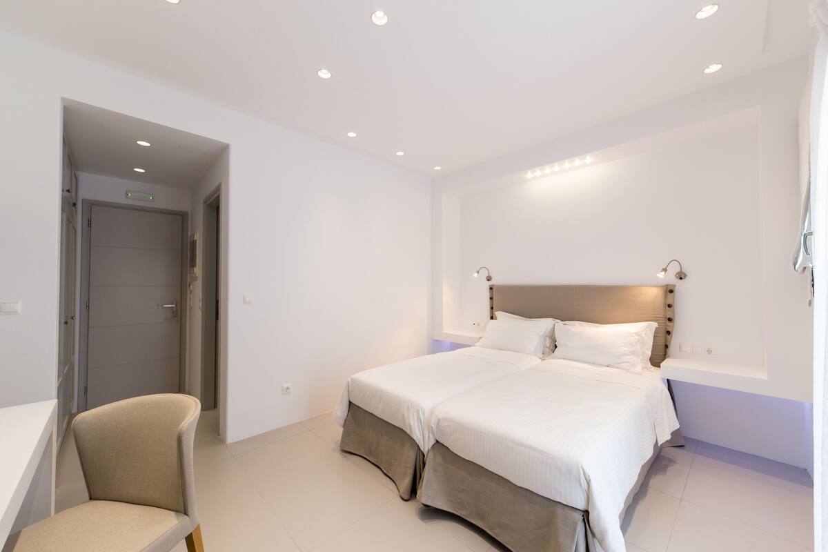 Quarto moderno com uma cama, uma cadeira e uma porta.
