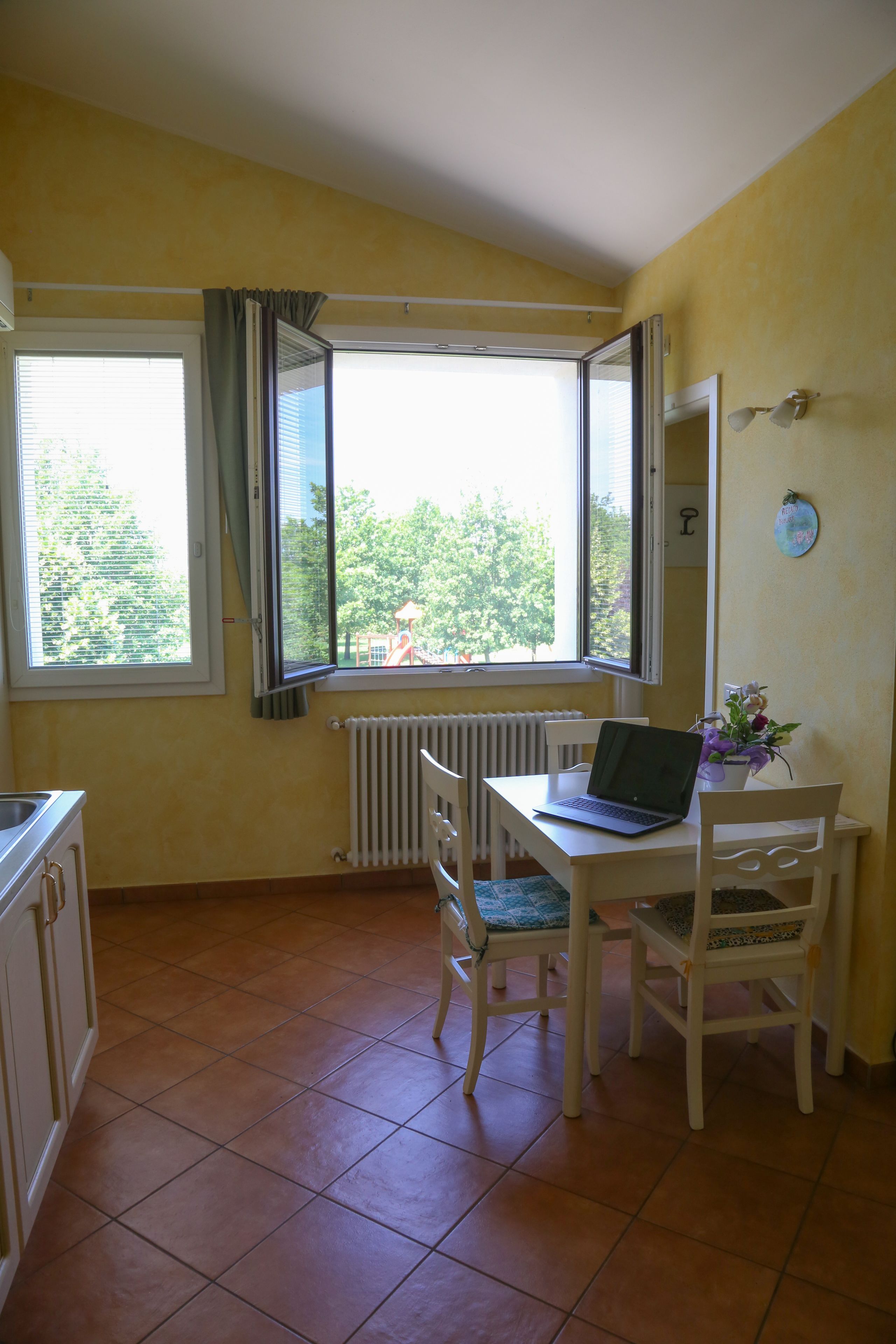 Uma cozinha compacta com uma mesa e cadeiras, uma janela com cortinas e um radiador.