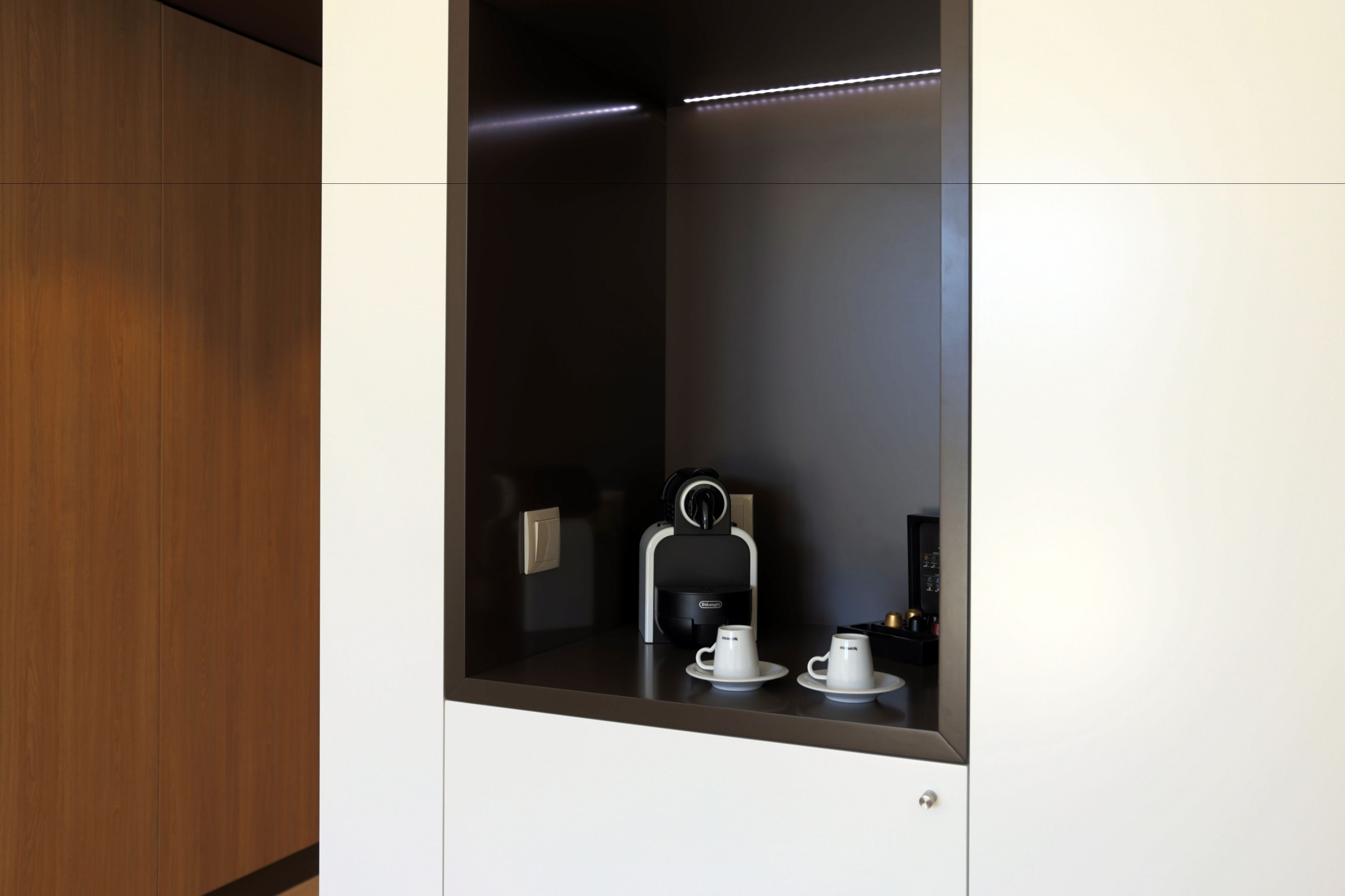 Uma estação de café moderna com uma máquina de café, duas chávenas e uma pequena mesa.