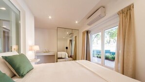 Quarto de hotel com uma cama grande, um espelho, uma janela com cortinas e um ar condicionado.