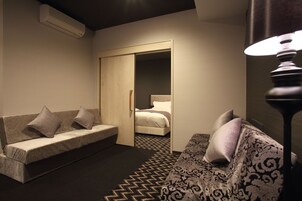 Quarto de hotel com sofá, tapete estampado e cama com cabeceira.