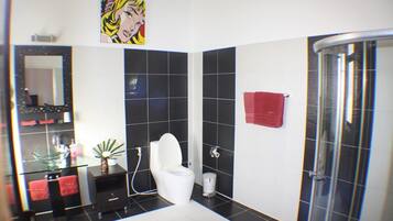Uma casa de banho moderna com sanita branca, azulejos pretos, lavatório de vidro e toalha vermelha.