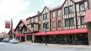 Um edifício em estilo Tudor tradicional com toldo vermelho, fachada de pedra e várias janelas.