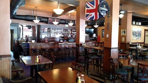 Uma área de bar com mobiliário de madeira, um letreiro da Guinness e uma bandeira do Reino Unido.