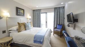 Quarto de hotel com uma cama, uma cadeira, uma televisão e um abajur.