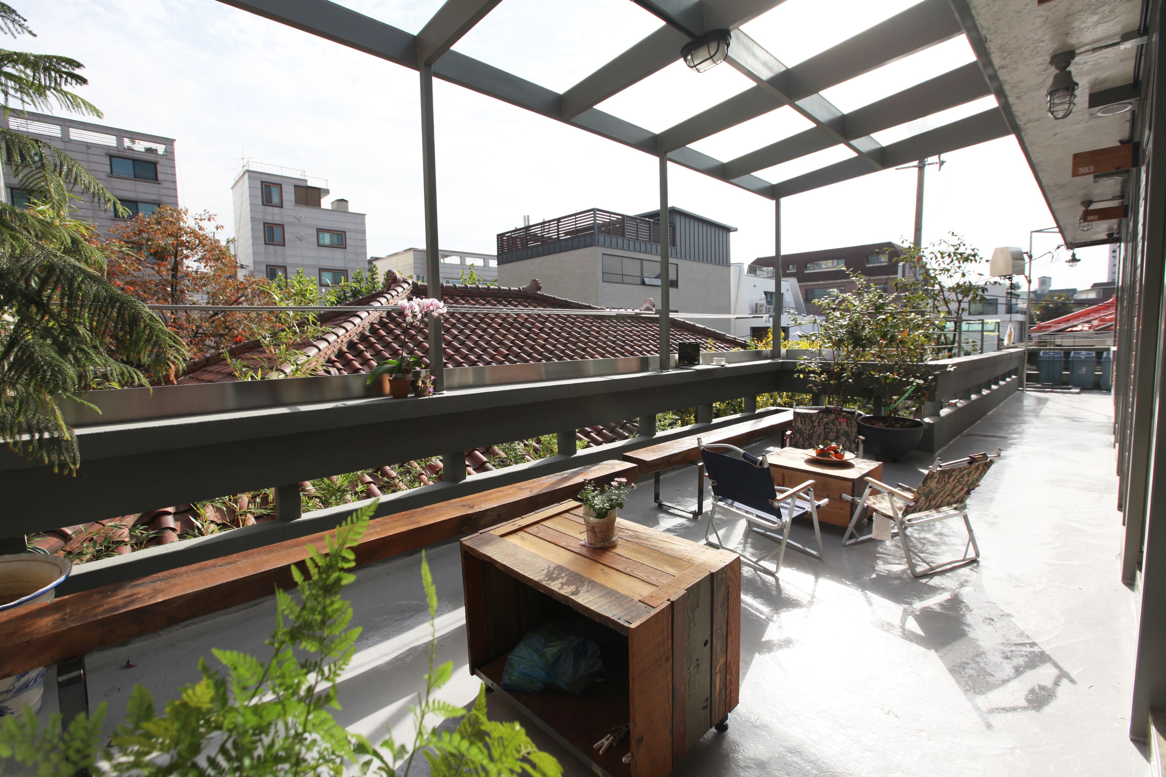 Terraço no telhado com área de estar ao ar livre, plantas em vasos e vista para a cidade.