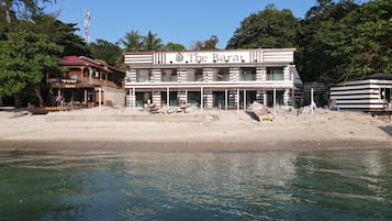 Um hotel na praia chamado 'The Barat', com área de recepção, vários quartos e vista para o mar.