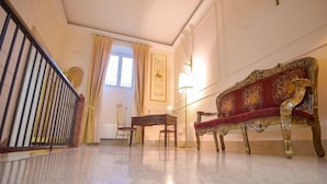 Um quarto com um amplo sofá vermelho estofado, uma escrivaninha de madeira e um candelabro.