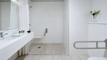 Uma casa de banho moderna com uma pia branca, espelho e chuveiro.