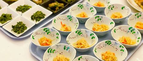 Uma bandeja com comida variada, incluindo recipientes com vegetais desfiados e uma porção com pequenas embalagens de folhas verdes.