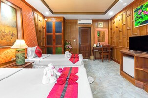 Quarto de hotel com duas camas, televisão, escrivaninha e um pequeno frigorífico.