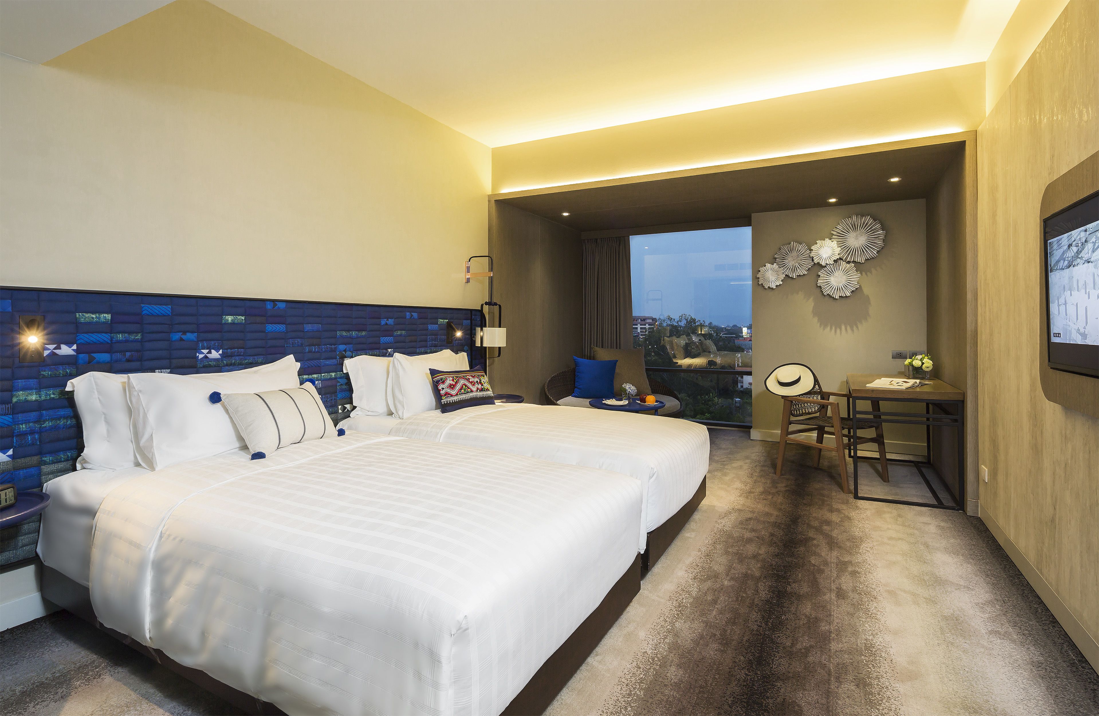 Quarto de hotel com uma cama grande, uma escrivaninha e vista para a cidade.