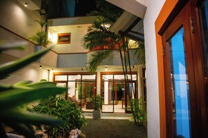 Um edifício moderno com entrada de vidro, plantas em ambiente interno e interior bem iluminado.