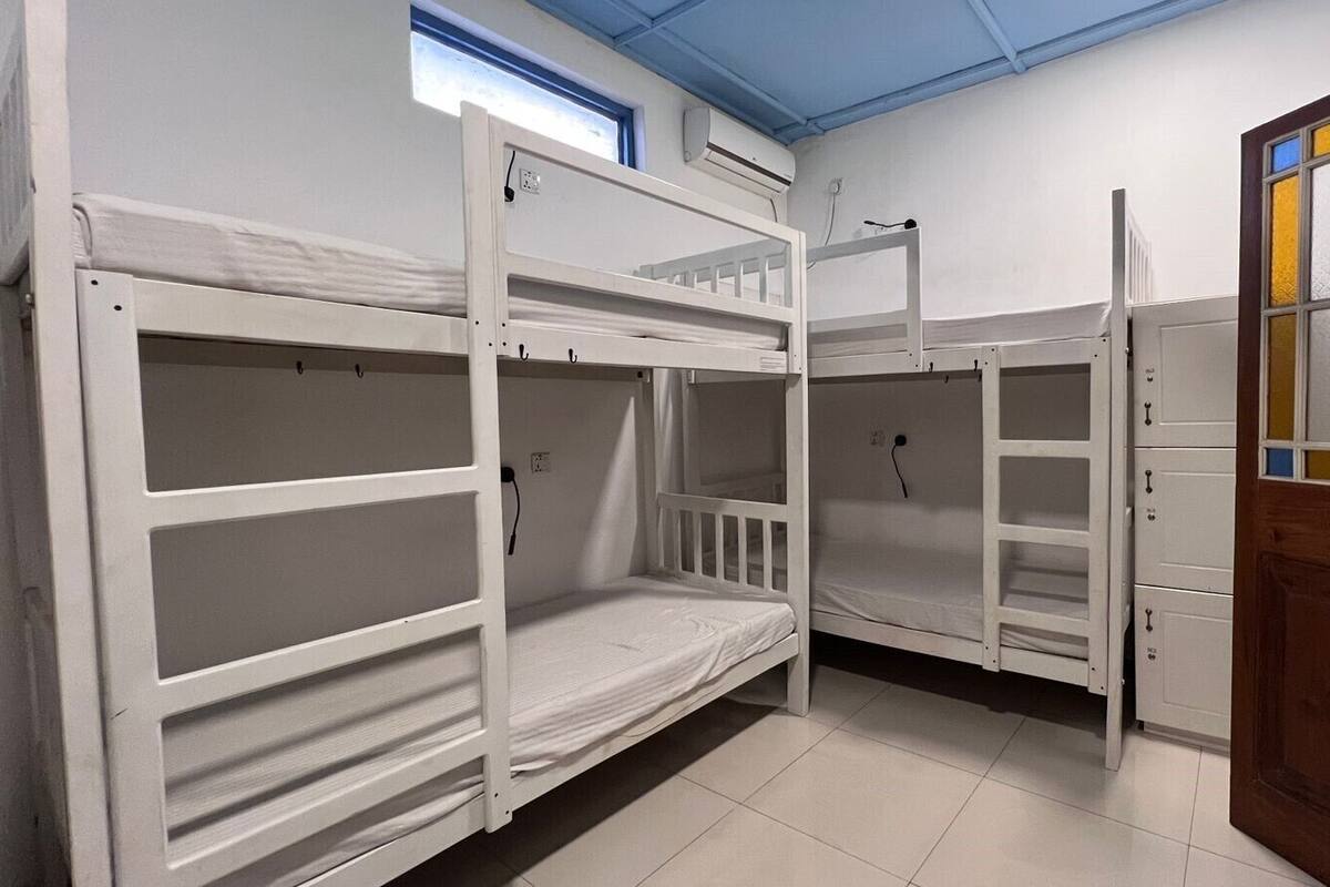 Quarto com beliche, janela, porta com painel de vidro e piso de azulejos.